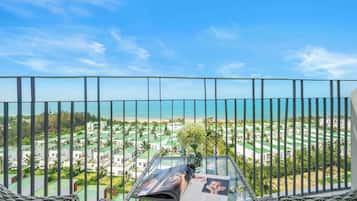 Uma varanda com vista desobstruída para a área de um resort, incluindo vários edifícios e uma praia.