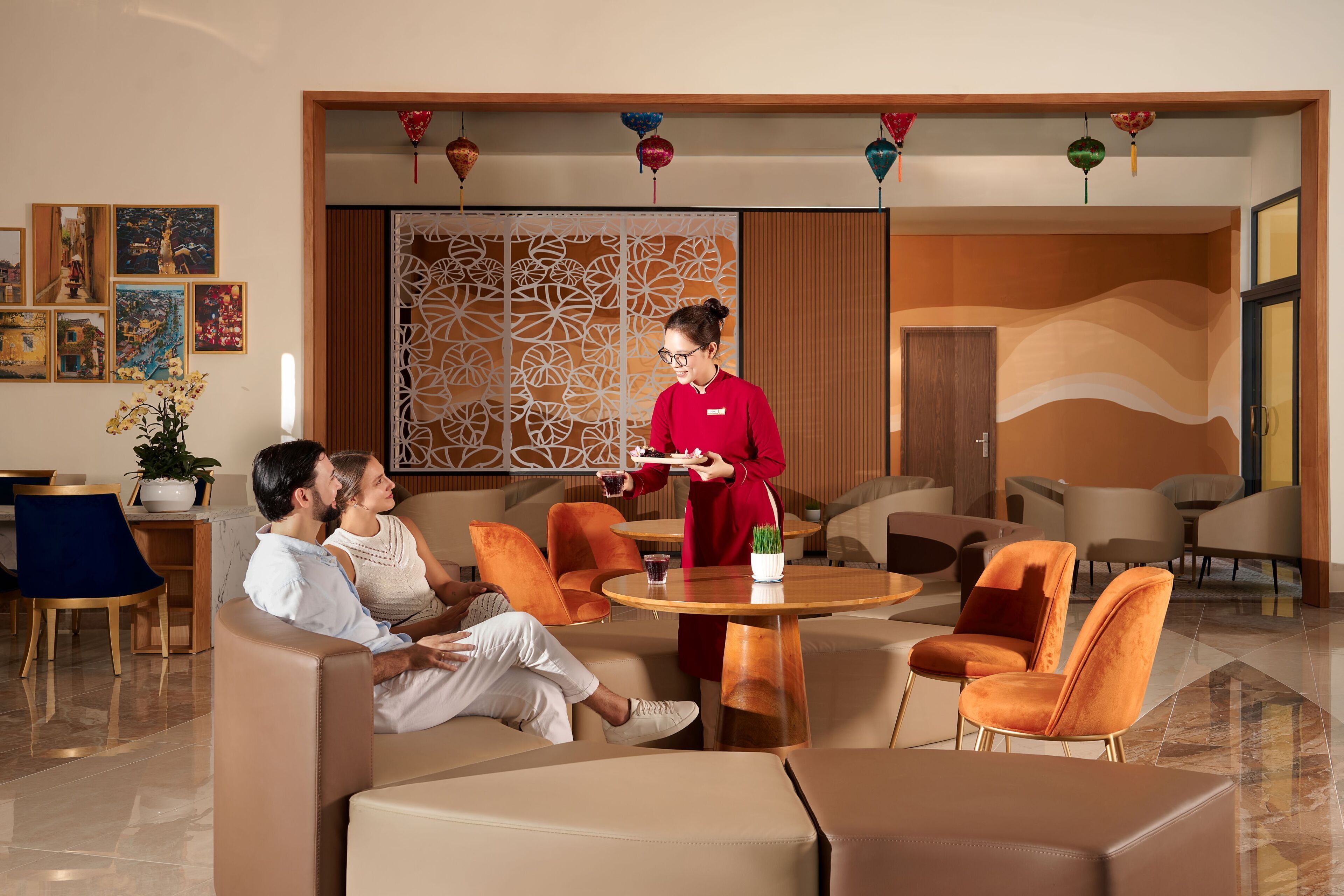 Um hall de hotel moderno com sofás de couro, um balcão de recepção de madeira e uma parede decorativa com enfeites pendurados.