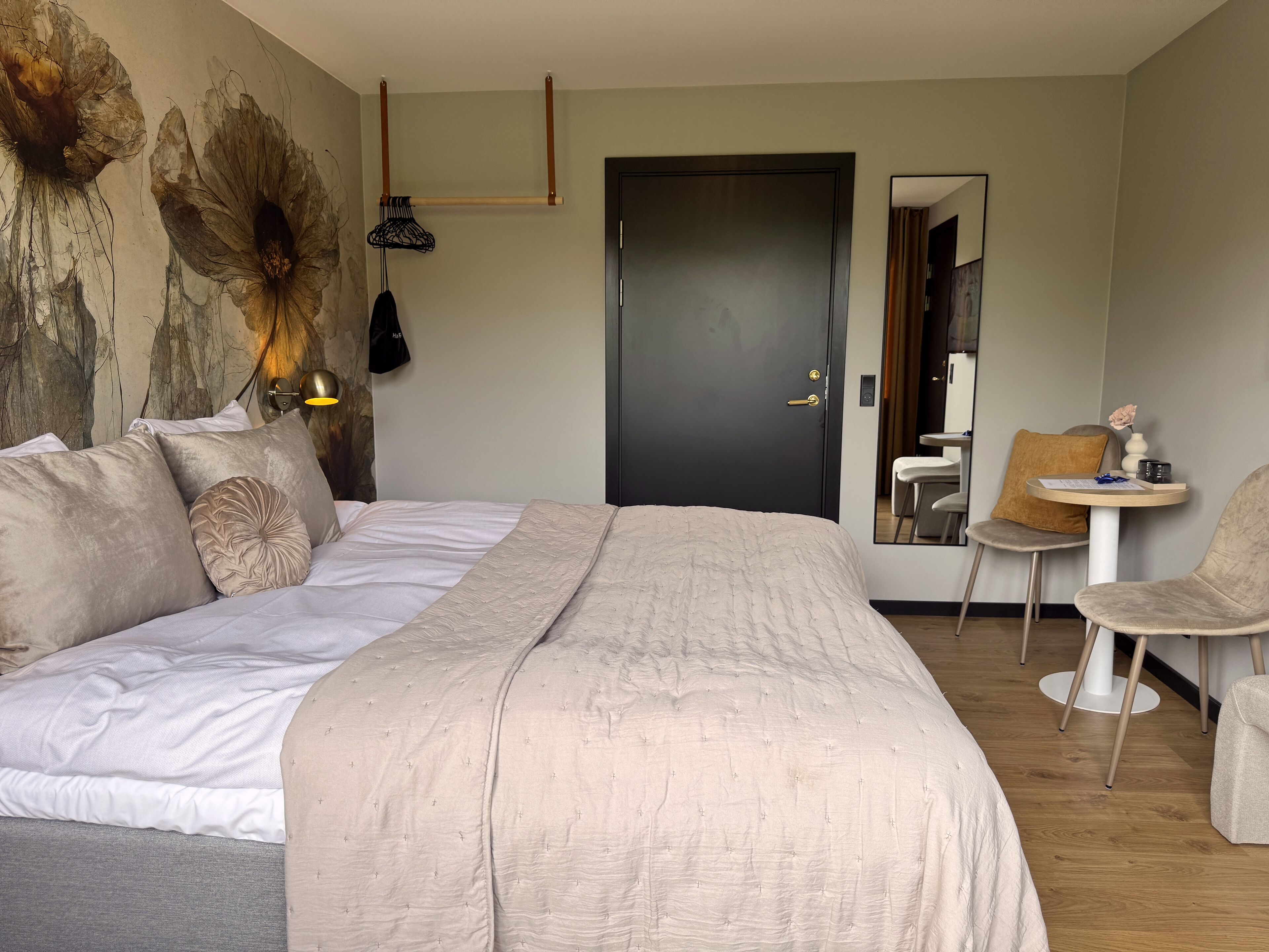 Quarto de hotel moderno com uma cama grande, uma mesa redonda pequena e uma cadeira.