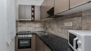 Uma cozinha compacta equipada com fogão, forno, micro-ondas e pia embutida.