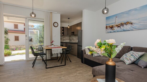 Uma sala de estar moderna com um sofá, uma mesa de jantar com cadeiras, uma cozinha ao fundo e um quadro na parede.
