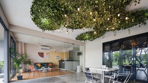 Um interior moderno com área de refeições, balcão de recepção e vista através de grandes janelas.