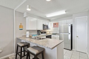 Condo com design assinado, 2 quartos, cozinha, vista para a praia | Cozinha privada | Geladeira, micro-ondas, fogão, cooktop