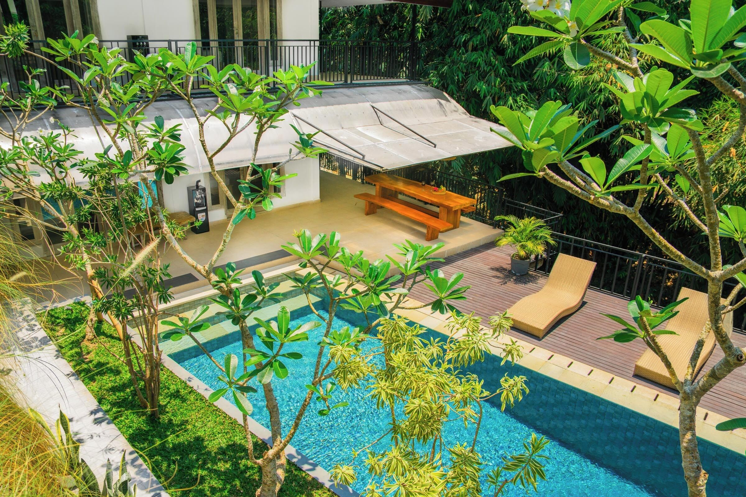 Área de piscina no terraço, com um banco de madeira, espreguiçadeiras e um pergolado.