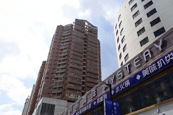 Um edifício alto com vários andares, uma loja com letreiros e um céu claro.