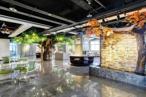Um interior moderno com piso refletivo, área de estar e uma árvore ornamental com folhagem verde.