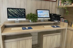 Uma mesa de madeira com dois monitores, teclado, rato e uma planta.