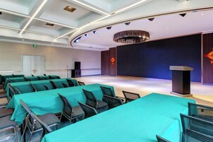 Uma sala de conferências com mesas alinhadas, palco e um púlpito.