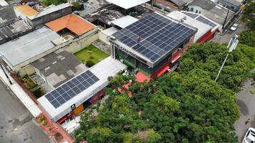 Um hostel com painéis solares no telhado, uma cobertura vermelha e uma área de jardim.