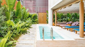 Área da piscina com espreguiçadeiras e deck de madeira.