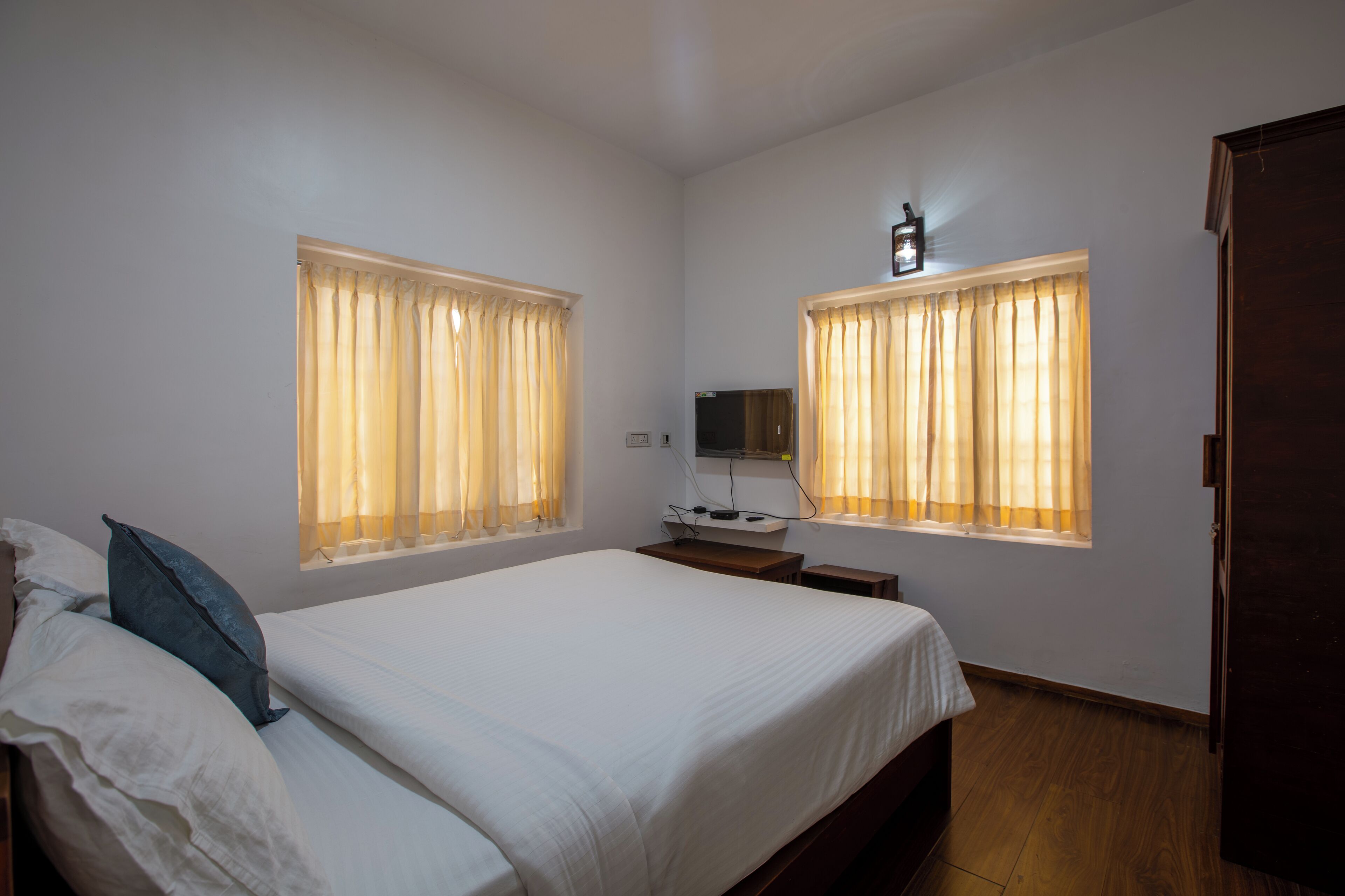 Um quarto com cama, mesas de cabeceira, televisão e cortinas.