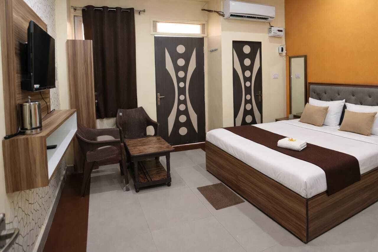 Quarto de hotel com cama, televisão, escrivaninha e cadeira.