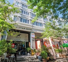 Hotel com placa, mesas ao ar livre e plantas em vasos.