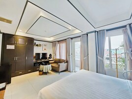 Quarto de hotel moderno com uma cama grande, um sofá, uma televisão e um guarda-roupa.
