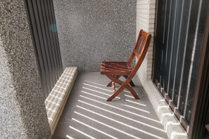 Uma cadeira de madeira num canto, com soalho em mosaicos e parede texturizada.