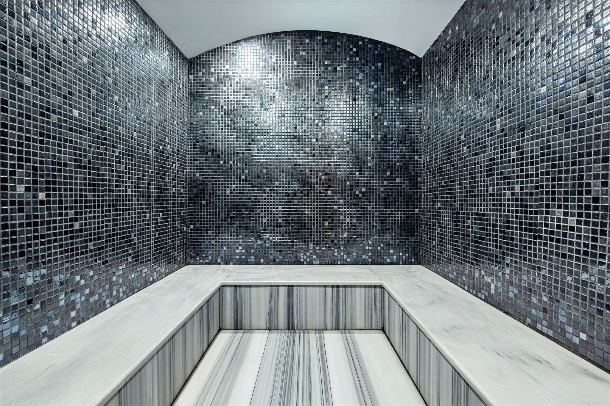 Um quarto com parede de azulejos e um banco de mármore.
