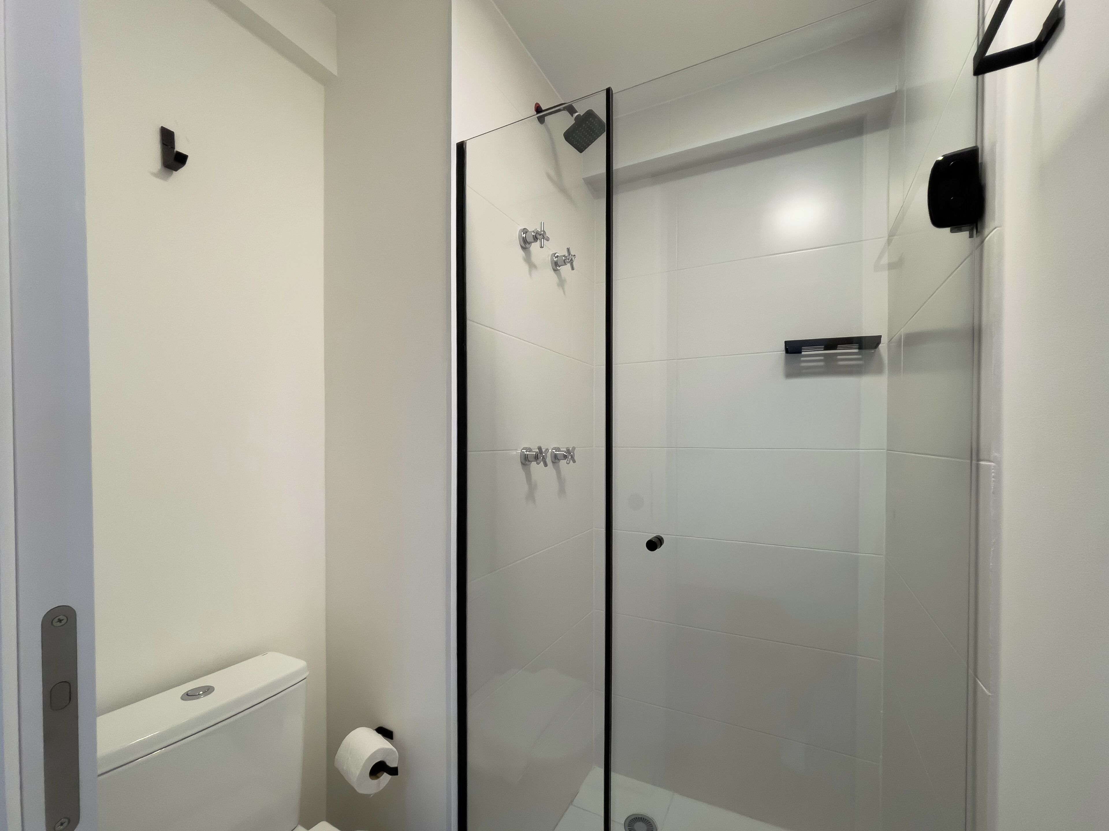 Um banheiro moderno com chuveiro em box de vidro, vaso sanitário e porta-toalhas.