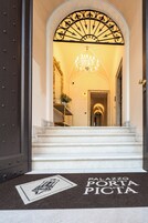 Uma entrada imponente com escadas de mármore, um candelabro e uma placa com a inscrição