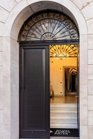 Uma entrada imponente com uma porta escura, um arco de metal decorativo e um candelabro.