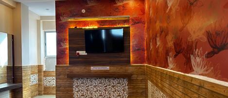Quarto de hotel com parede de madeira, televisão montada acima de uma lareira e design de parede estampado.