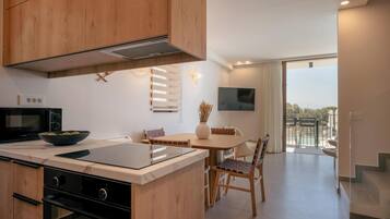 Cozinha moderna com ilha central, armários de madeira, forno embutido e área de jantar com mesa e cadeiras.