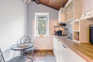 Cozinha compacta com área de jantar, janela com vista e teto de madeira.
