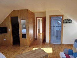Interior em madeira com um quarto em mezzanine, um banheiro com chuveiro e uma placa com a inscrição 'Barry's Irish cottage'.