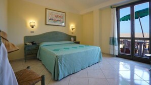 Quarto com cama, mesas de cabeceira, um apoio para objetos, uma cadeira, janela com vista e varanda com guarda-sol.