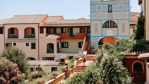 Um pátio com edifícios com arquitetura tradicional mediterrânea, incluindo varandas arqueadas e telhados de terracota.