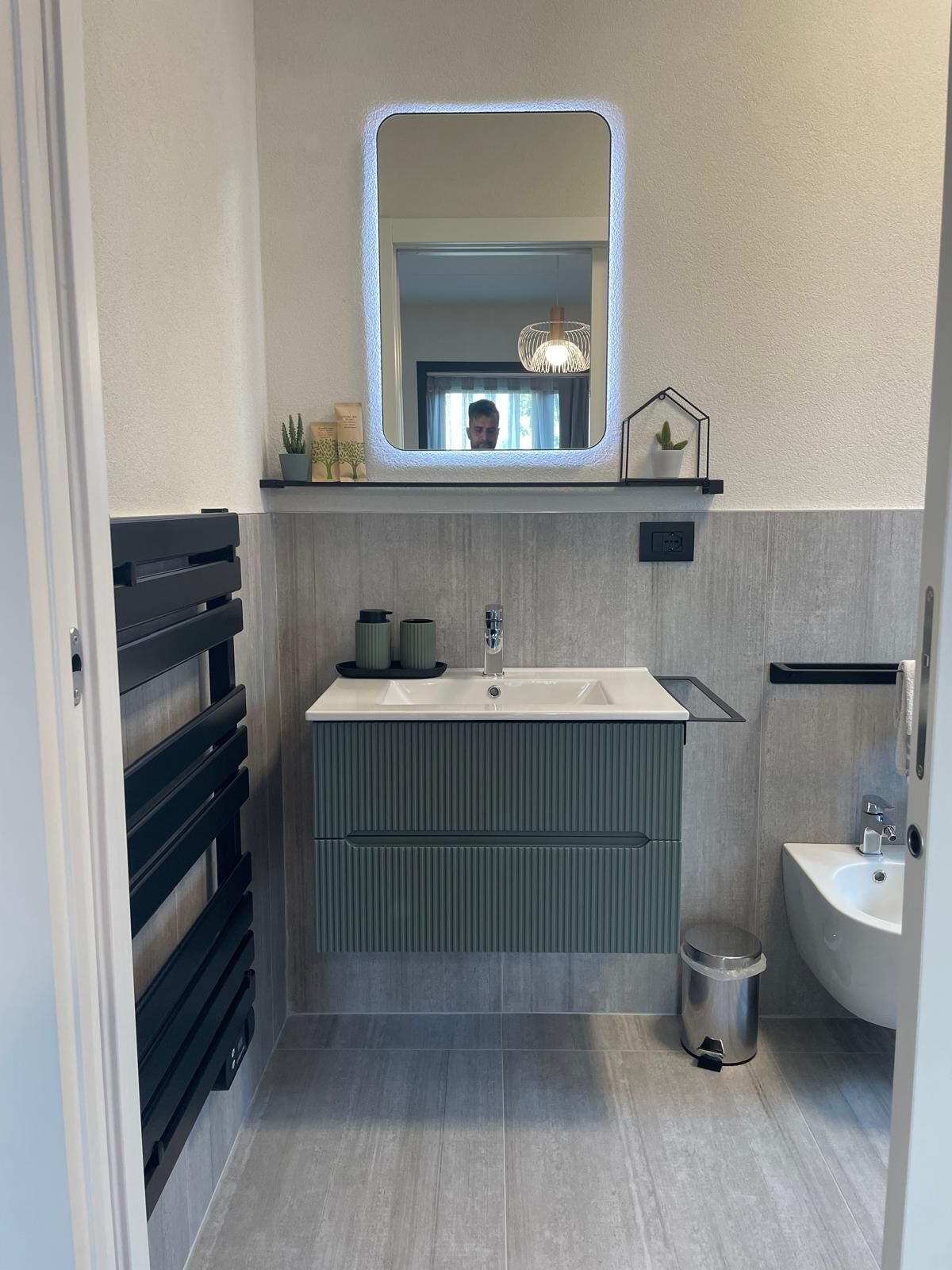 Uma casa de banho moderna com um espelho grande, uma toucador com lavatório e um lavatório pedestal separado.