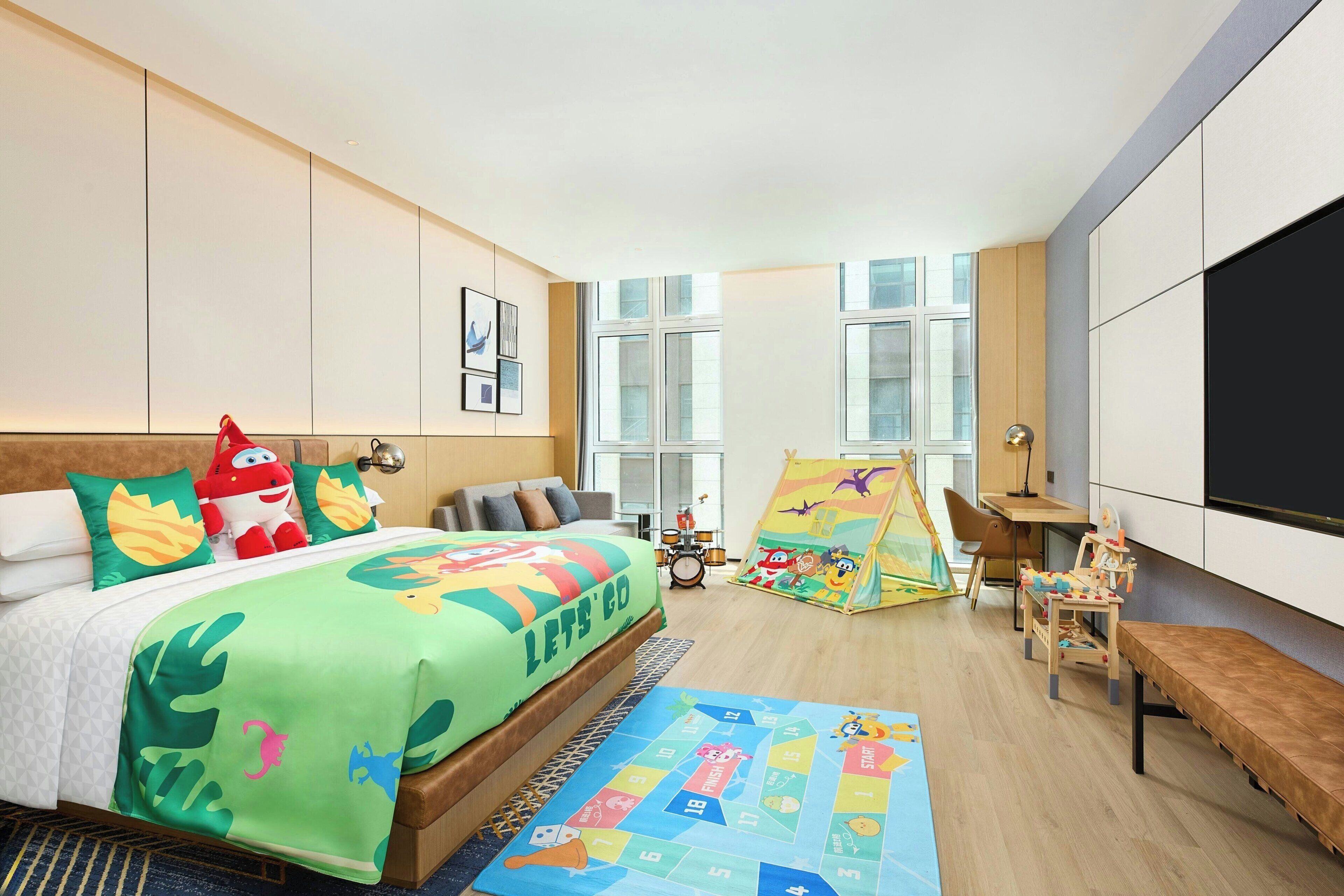 Quarto para crianças, com cama, espaço para brincar e uma televisão grande.