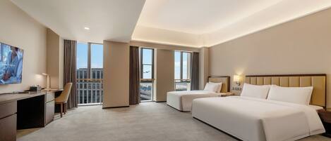 Quarto de hotel com escrivaninha, duas camas, televisão e vista para a cidade.