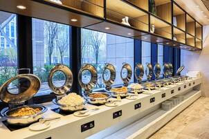 Buffet com várias estações de comida, cada uma com uma bandeja de metal.