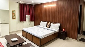 Quarto com cama, mesa de cabeceira, uma mesinha e uma cadeira vermelha.