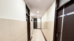 Um corredor com paredes e chão revestidos de azulejos, e portas em ambos os lados.
