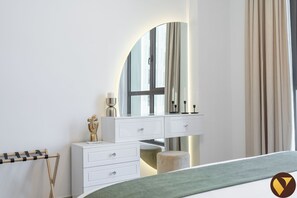 Quarto moderno com penteadeira branca, espelho e colcha verde.