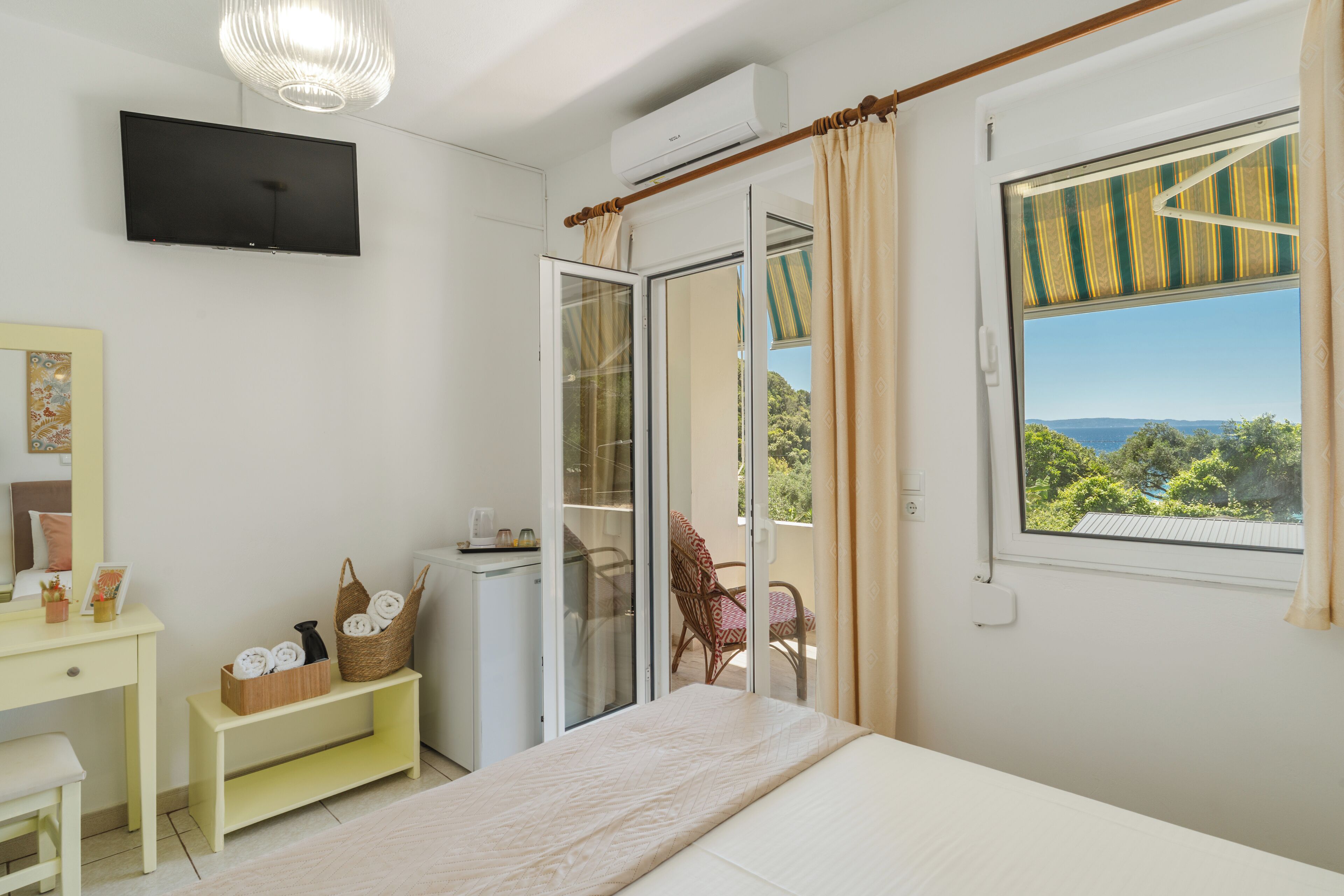 Quarto com cama, escrivaninha, cadeira, televisão e janela com vista.