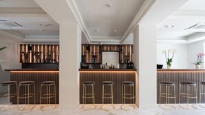 Uma área de bar moderna, com piso de mármore, três bancos e um balcão repleto de garrafas.