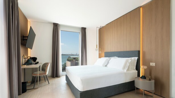 Quarto de hotel moderno com uma cama grande, uma escrivaninha e uma cadeira.