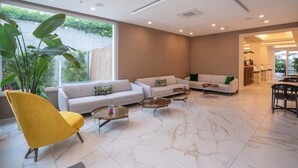 Uma sala de estar moderna com sofá, poltrona, mesa de centro e uma área de jantar com cadeira e mesa.