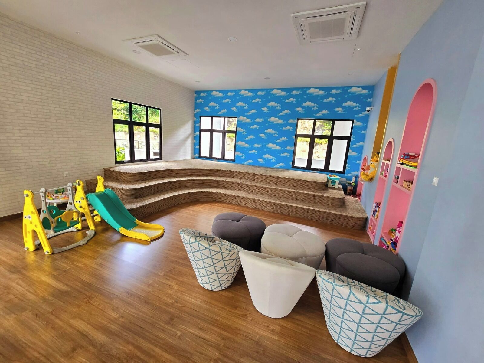 Uma sala de brinquedos com piso de madeira, um escorrega e uma escada curva.