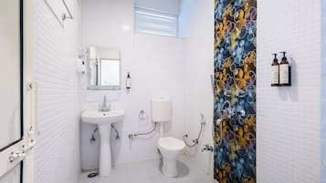 Um banheiro com parede de azulejos brancos, pia, vaso sanitário e cortina de chuveiro com padrão circular.