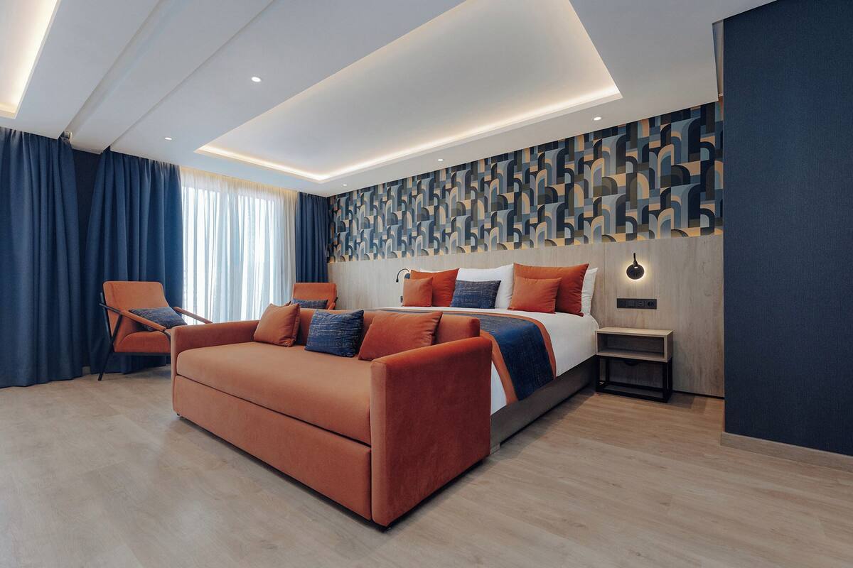 Quarto moderno com uma cama grande, um sofá e uma mesa de cabeceira.
