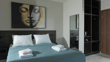 Quarto de hotel moderno com uma cama grande, um guarda-roupa, um espelho e um quadro na parede.