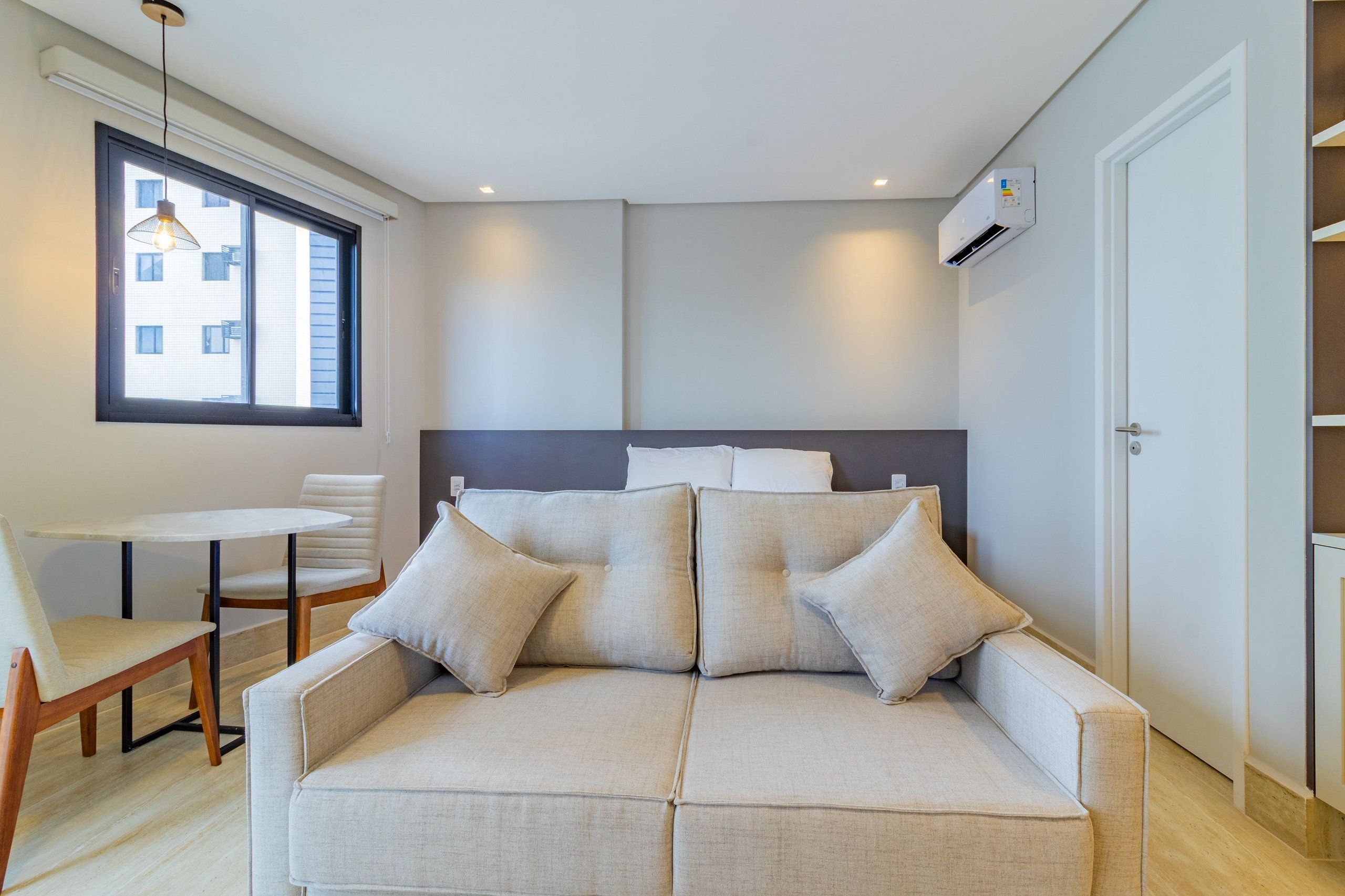 Quarto moderno com sofá-cama, uma mesinha e cadeiras.