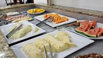 Buffet com diversos alimentos, incluindo frutas e legumes fatiados.
