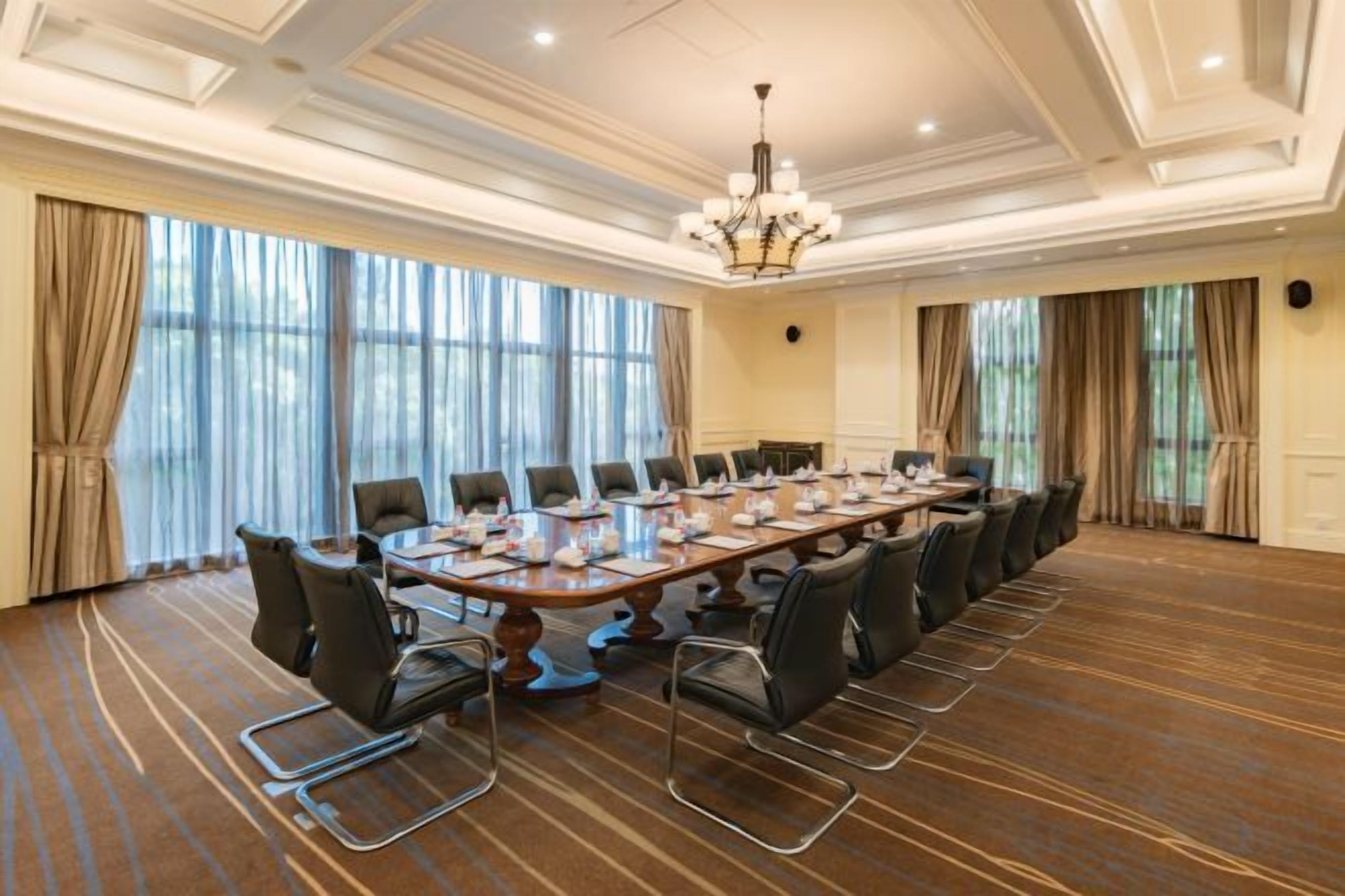 Sala de conferência com uma mesa comprida, várias cadeiras e um candelabro.