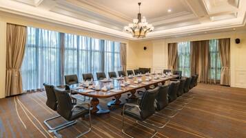 Sala de conferência com uma mesa comprida, várias cadeiras e um candelabro.