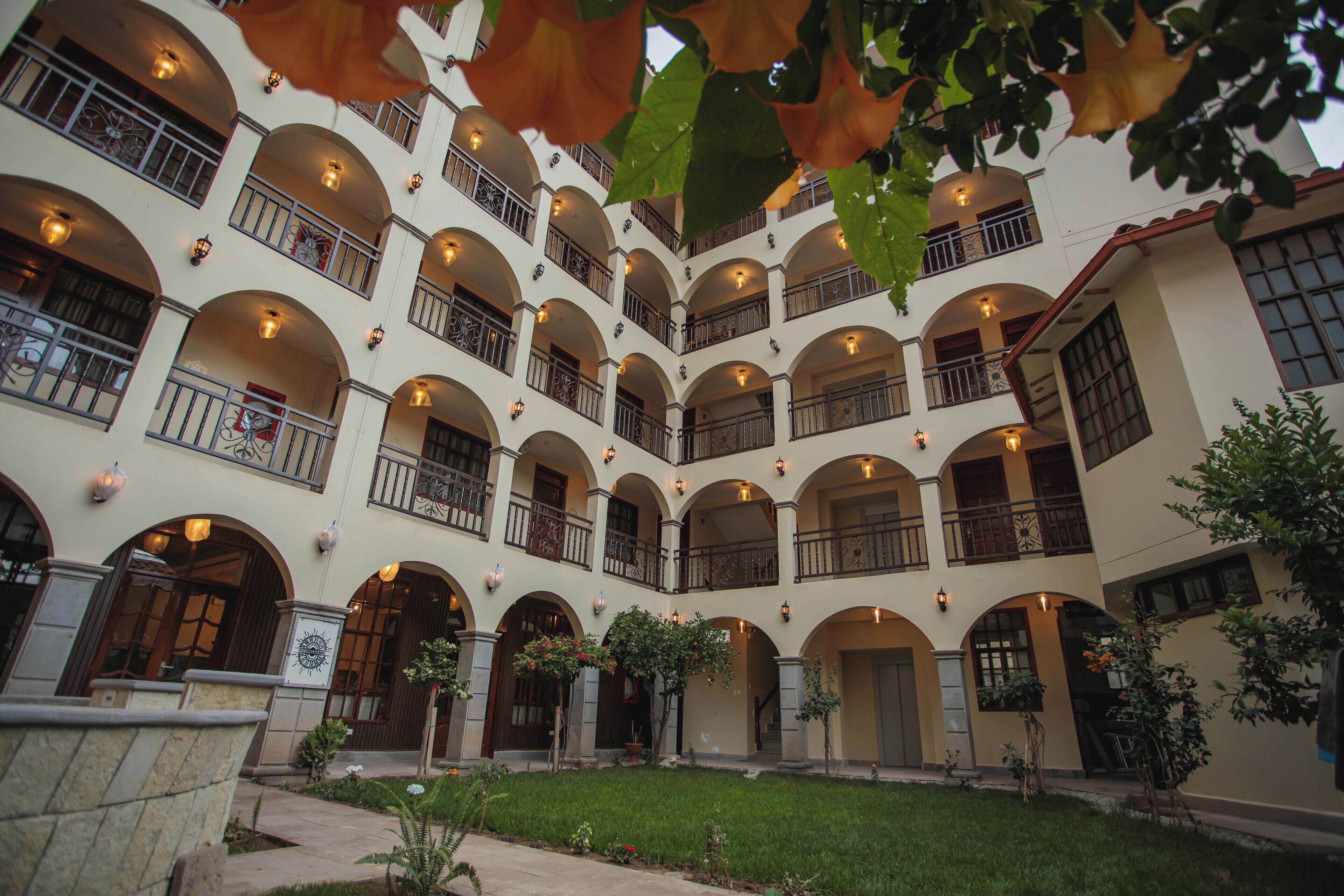 Edifício de vários andares com um pátio central, com varandas e guarda-corpos, portas arqueadas e iluminação externa.