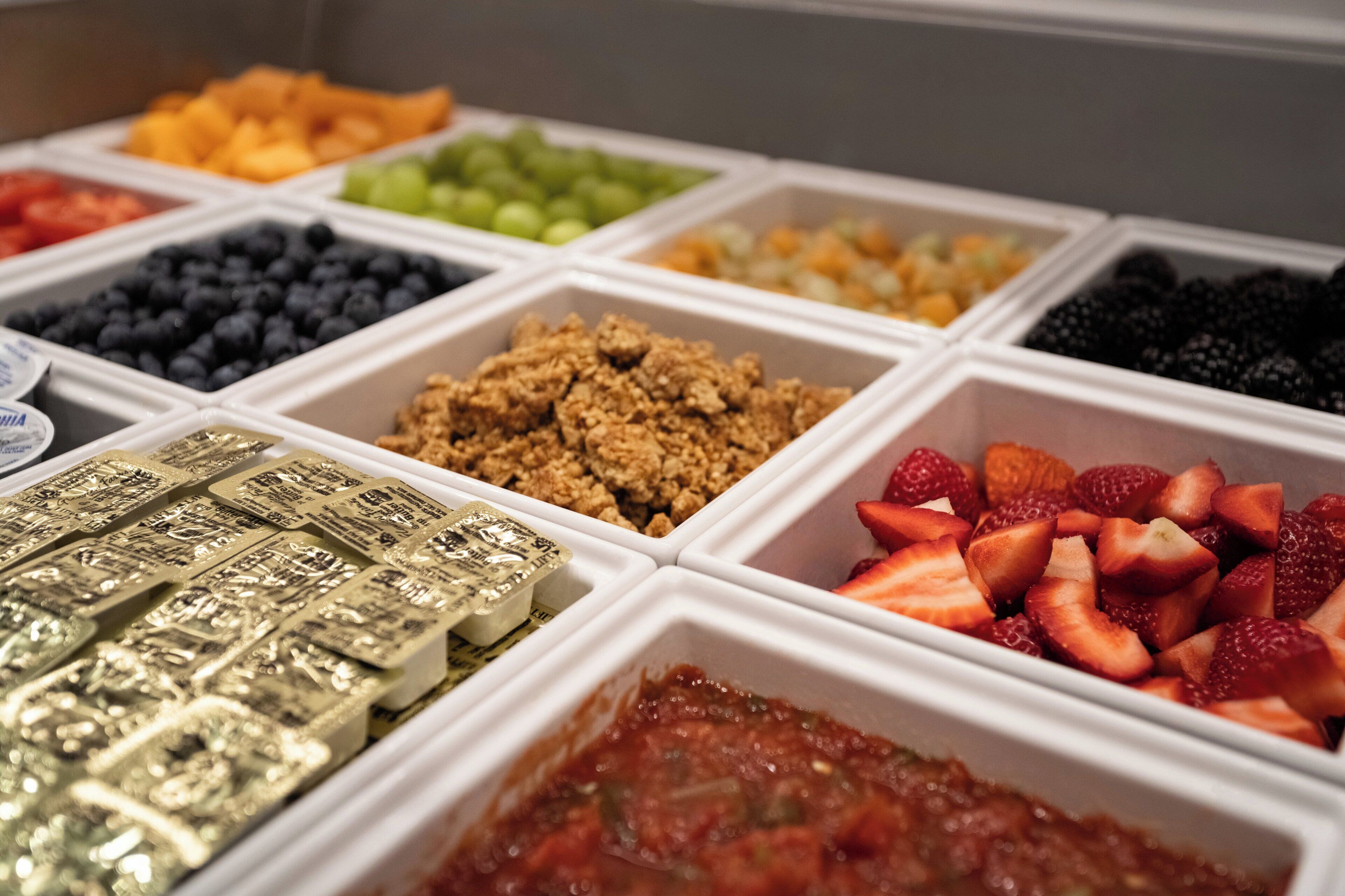 Exposição de alimentos com diversas frutas e barras de granola.